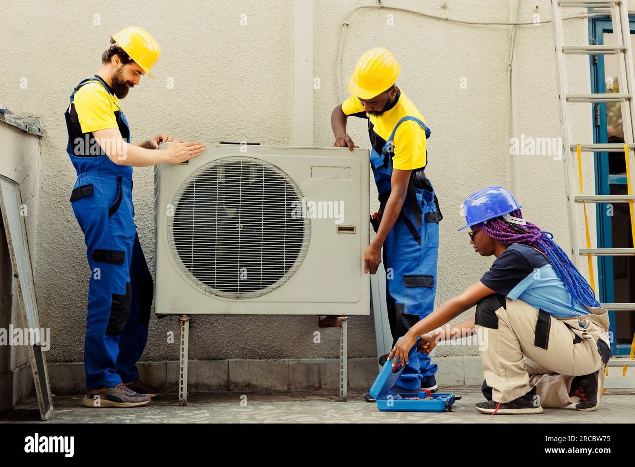 Seasoned mechanic coworkers installing outside air conditioner for customer. Adept repairmen ...