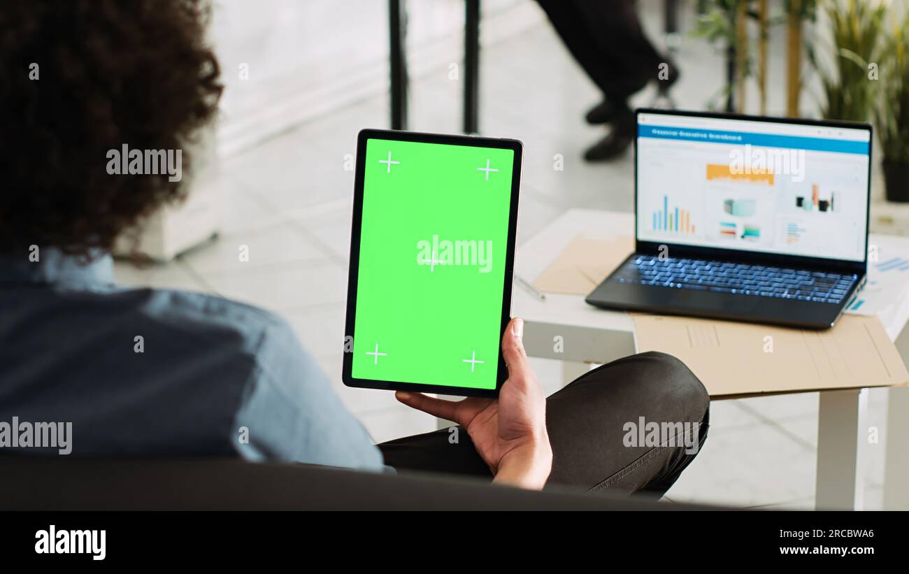 Analyst holding device with greenscreen looking at annual statistics ...