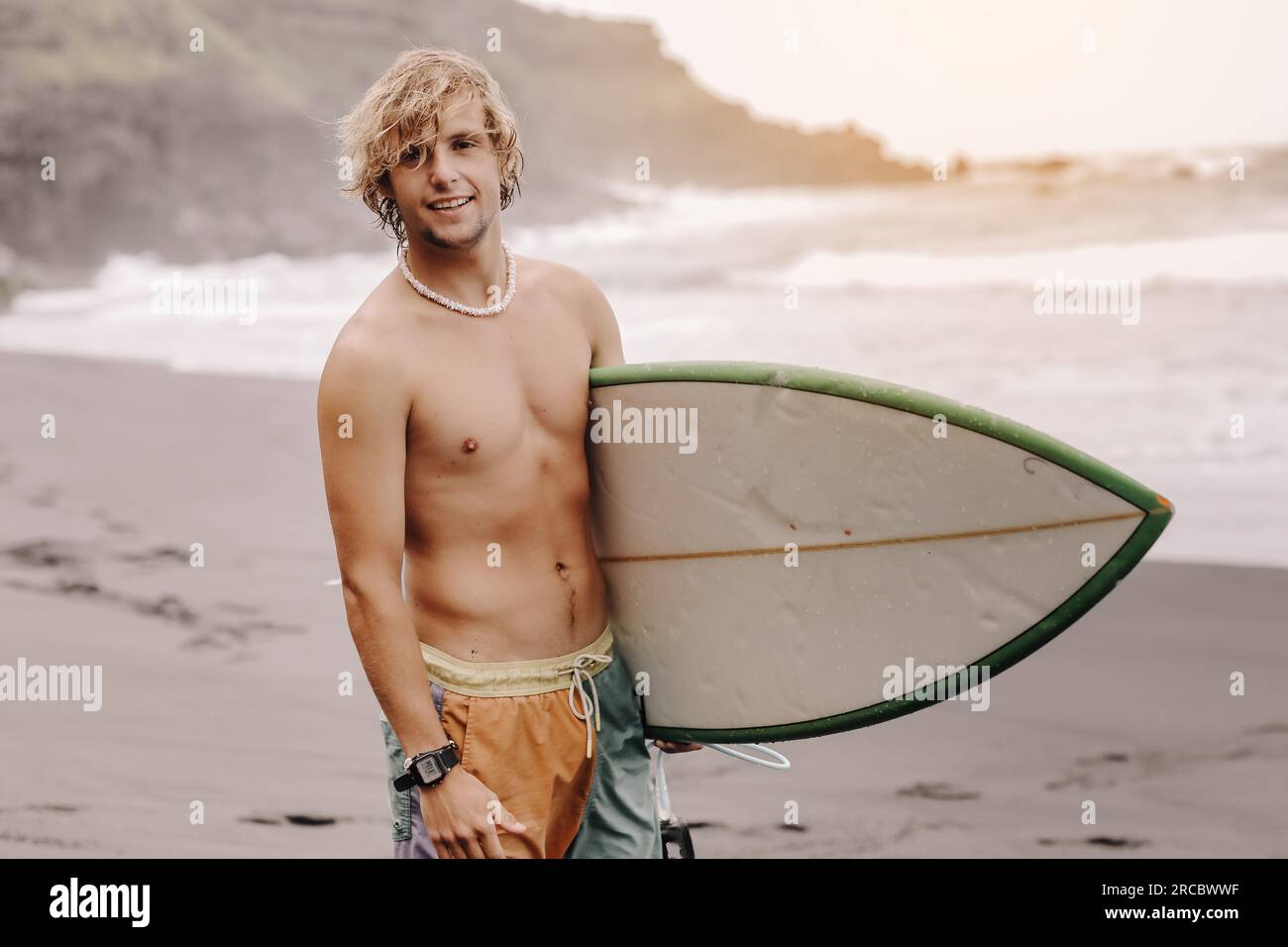 Handsome fit young blond man with mock up surfboard waits for wave to ...
