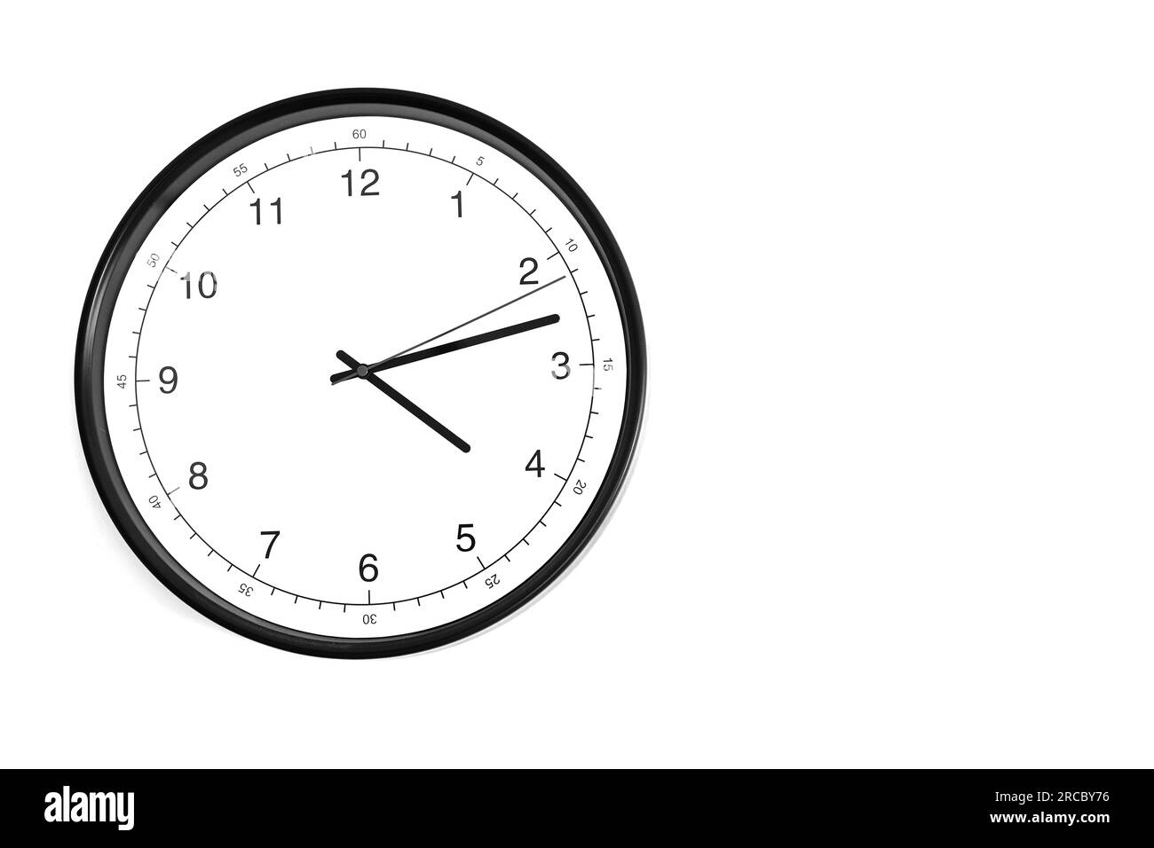 Part of analogue plain wall clock on white wall background. Four o ...