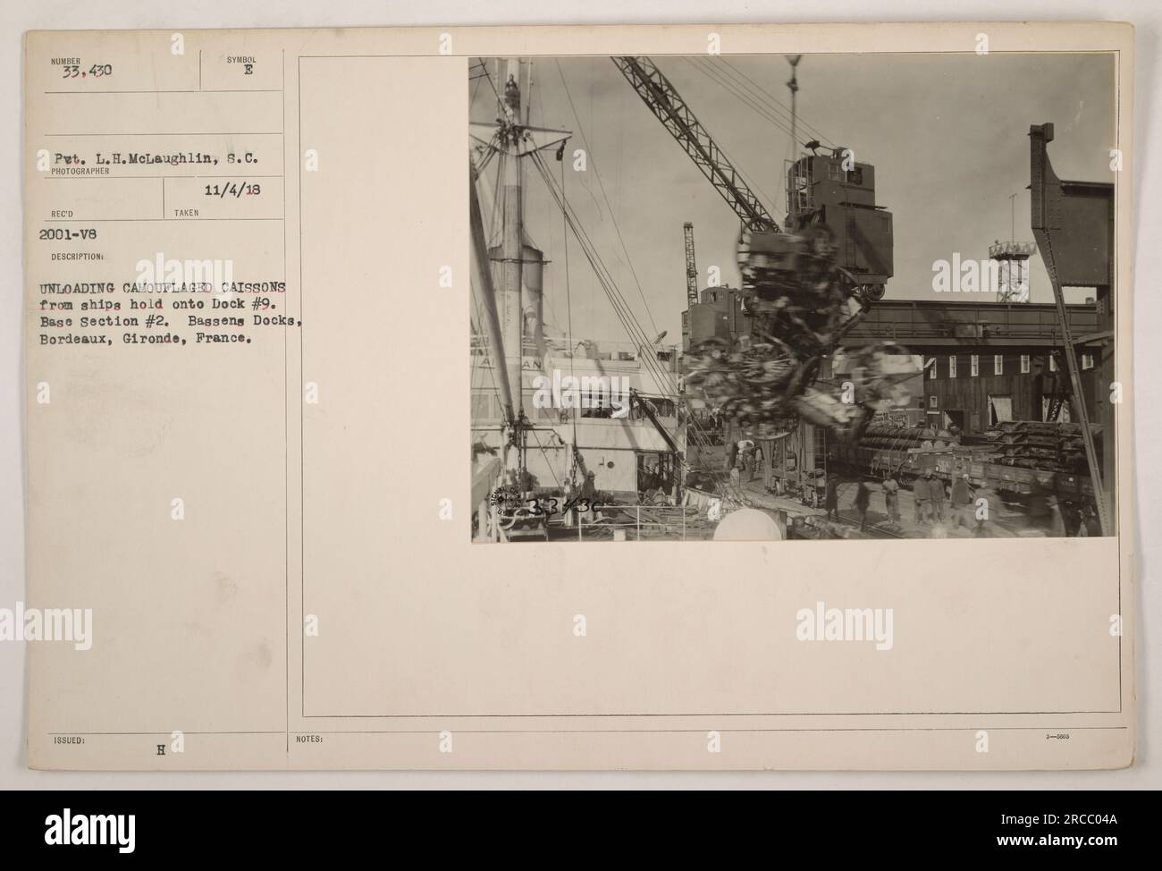 Soldiers unloading camouflaged caissons from a ship hold onto Dock #9 ...