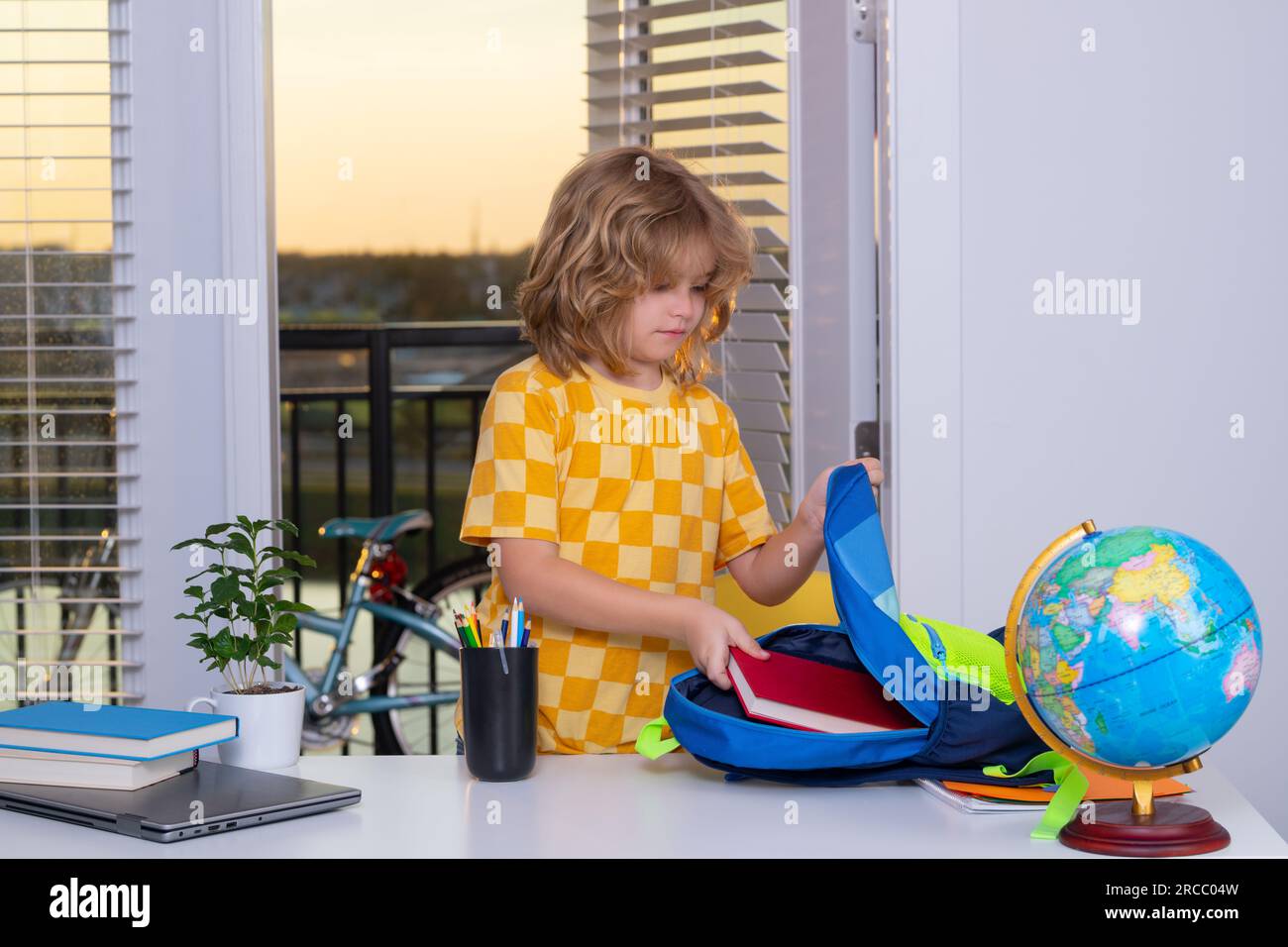 School child puts school supplies in a backpack at home. Kid from ...
