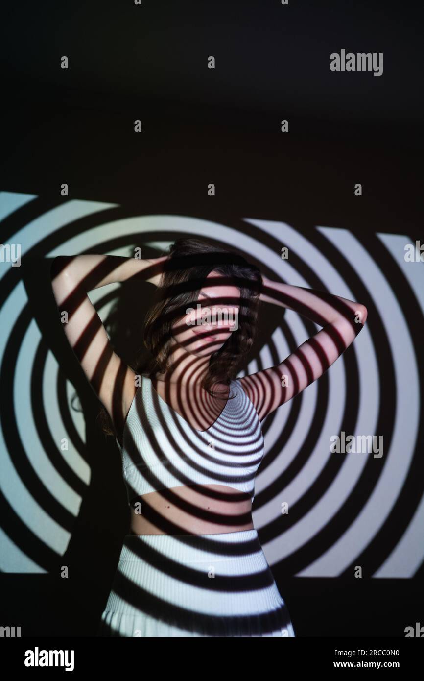 young adult woman or teenager girl in trendy outfit in dark room with ...