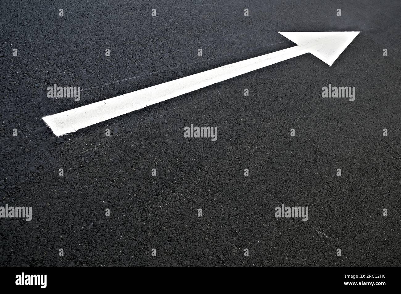 White arrow gives traffic direction, white reflective paint on a black ...