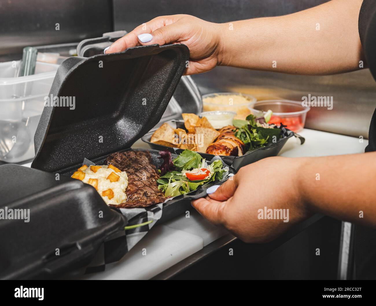 A hand with gloves closing a lunch of risotto with stake ready for ...