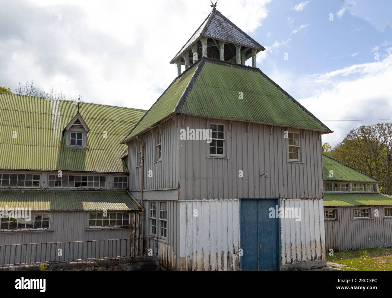 Old tin sheet building painted green and grey with a unique pointed ...
