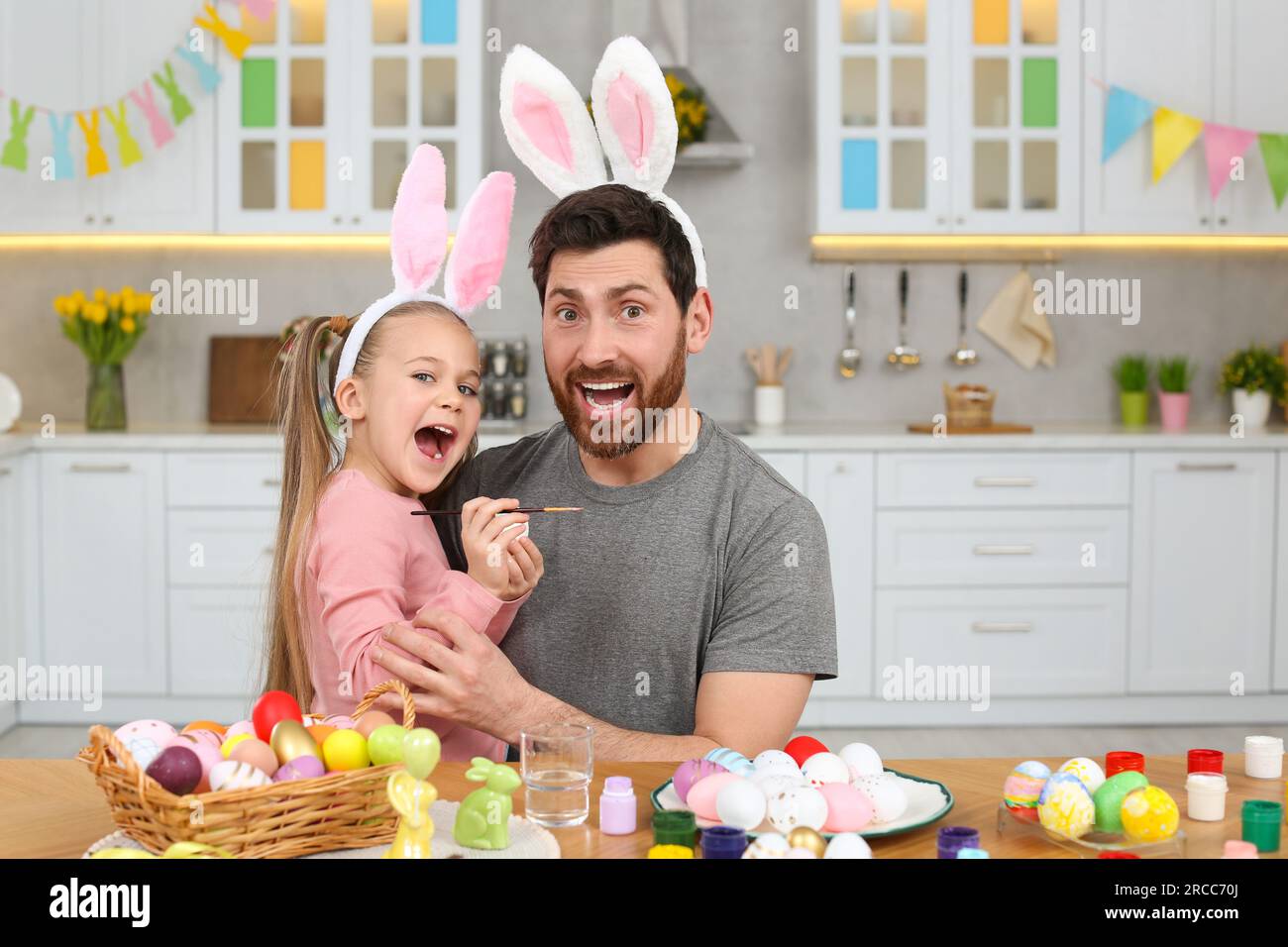 Emotional father with his cute daughter and Easter eggs at table in ...