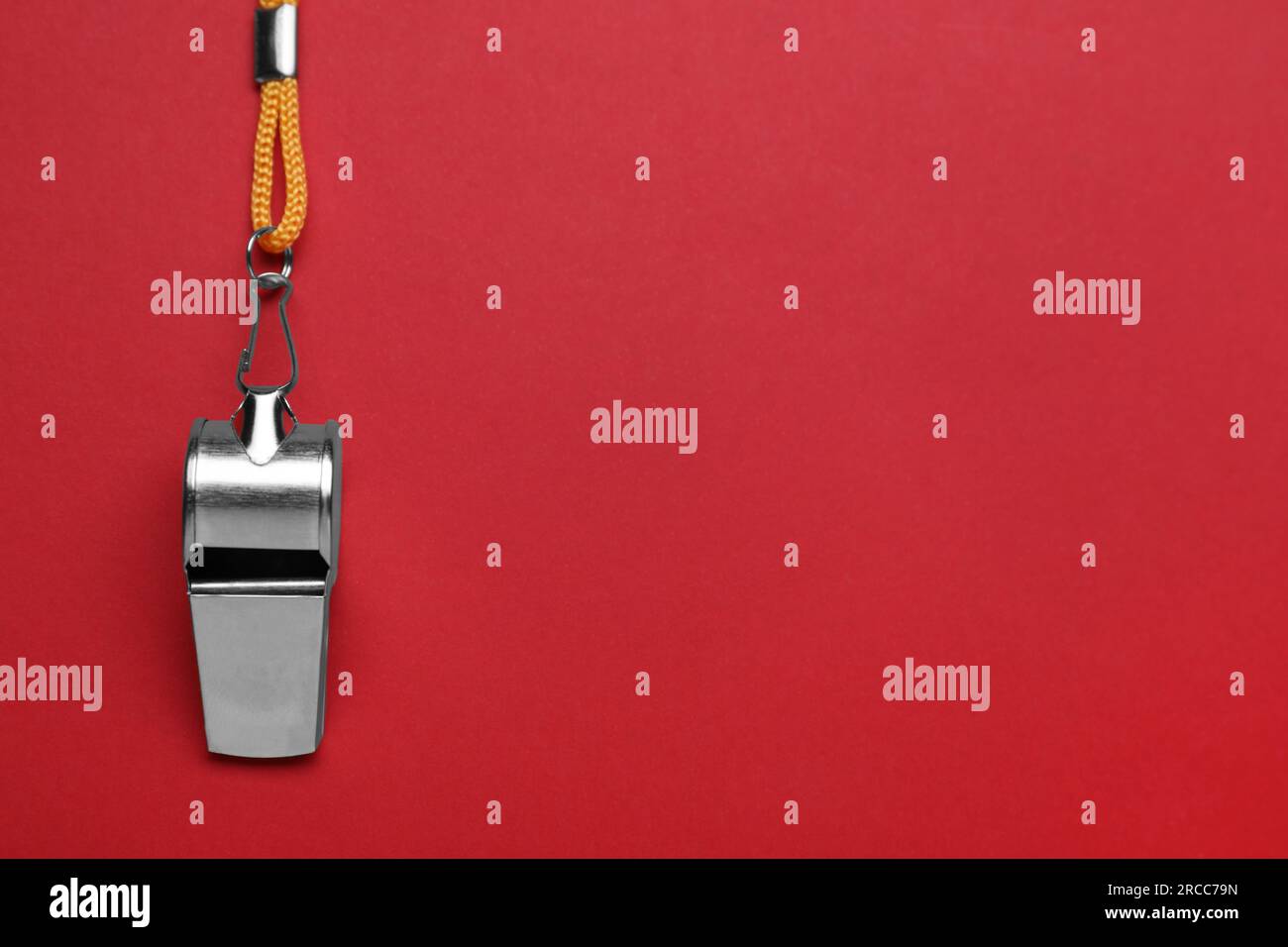 One metal whistle with cord on red background, top view. Space for text ...