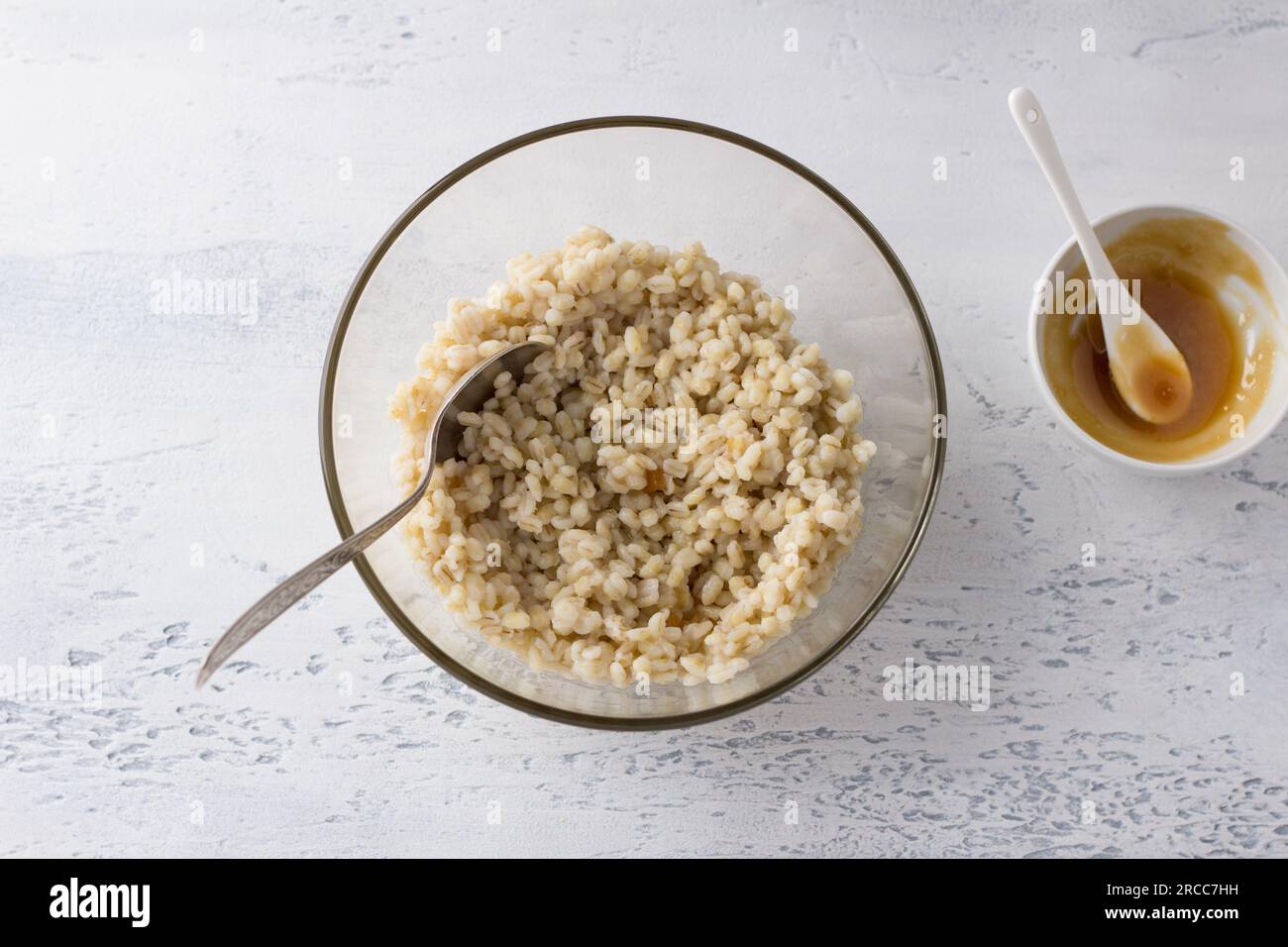 Barley with honey in a glass bowl on a light blue background, top view ...