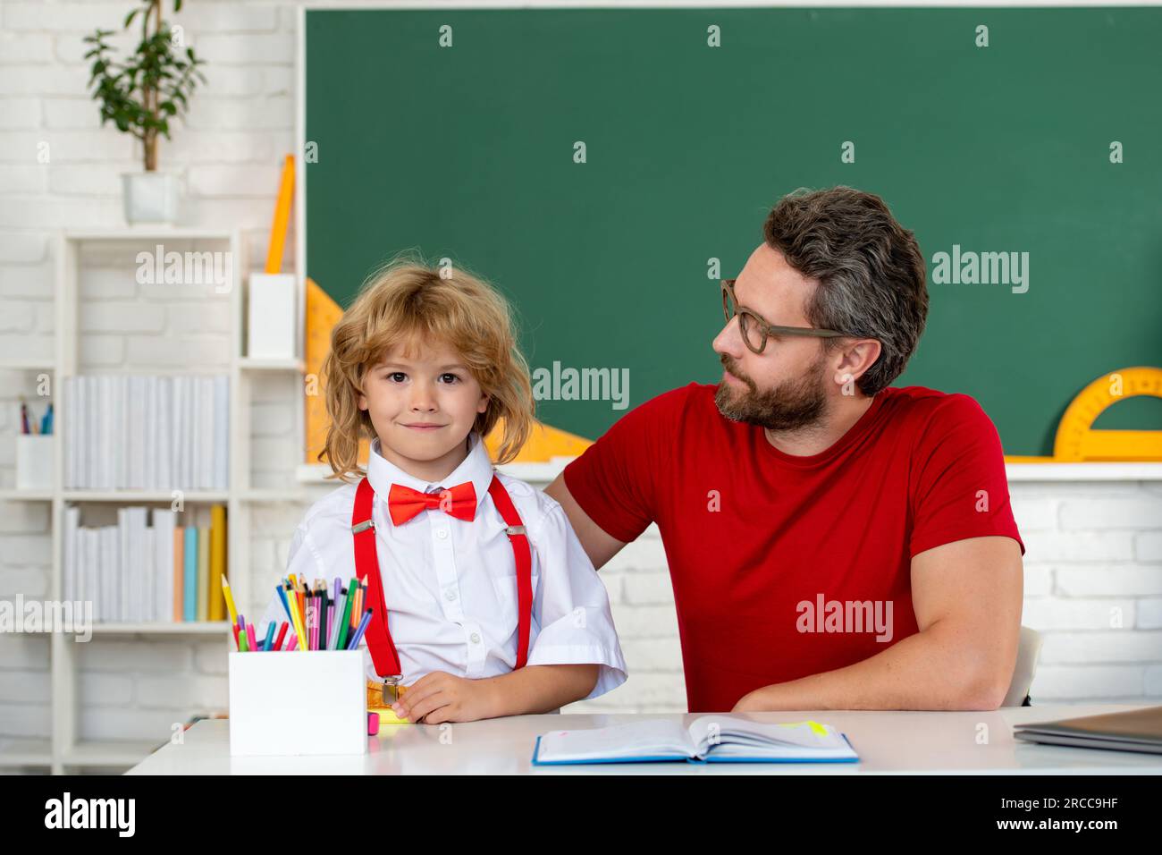 First day at school. Cute little boy studying lesson in class ...