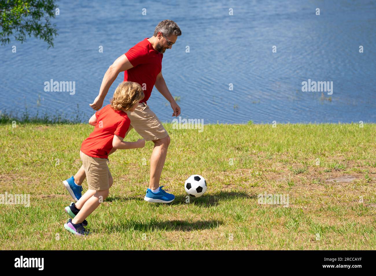 Father and son enjoy a friendly game of football. Practice passing and ...