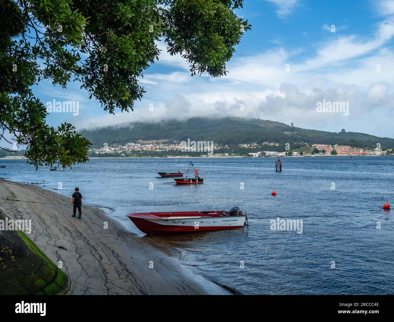 A man is seen standing close to his boat. The Coastal Route of the ...