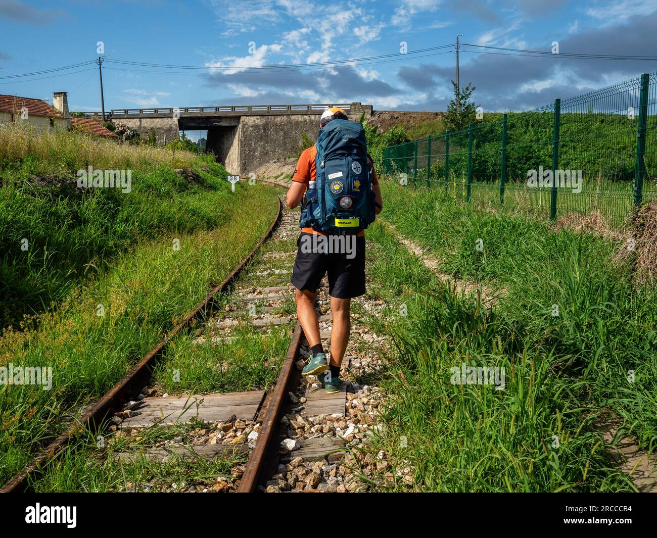 A pilgrim is seen walking close to a railroad track. The Coastal Route ...