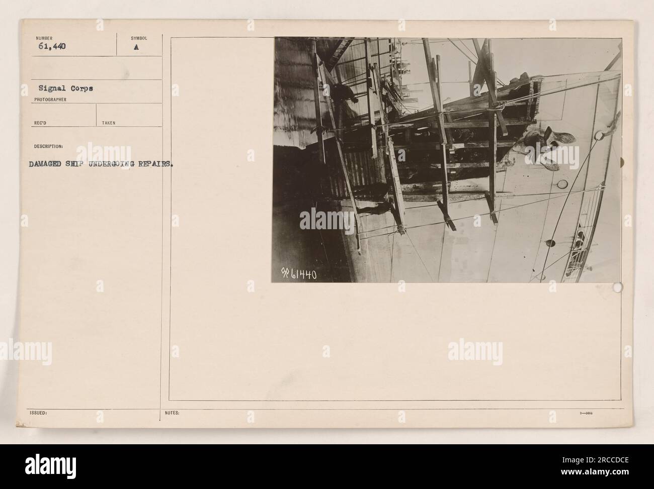 The image shows a damaged ship undergoing repairs. It is part of the ...