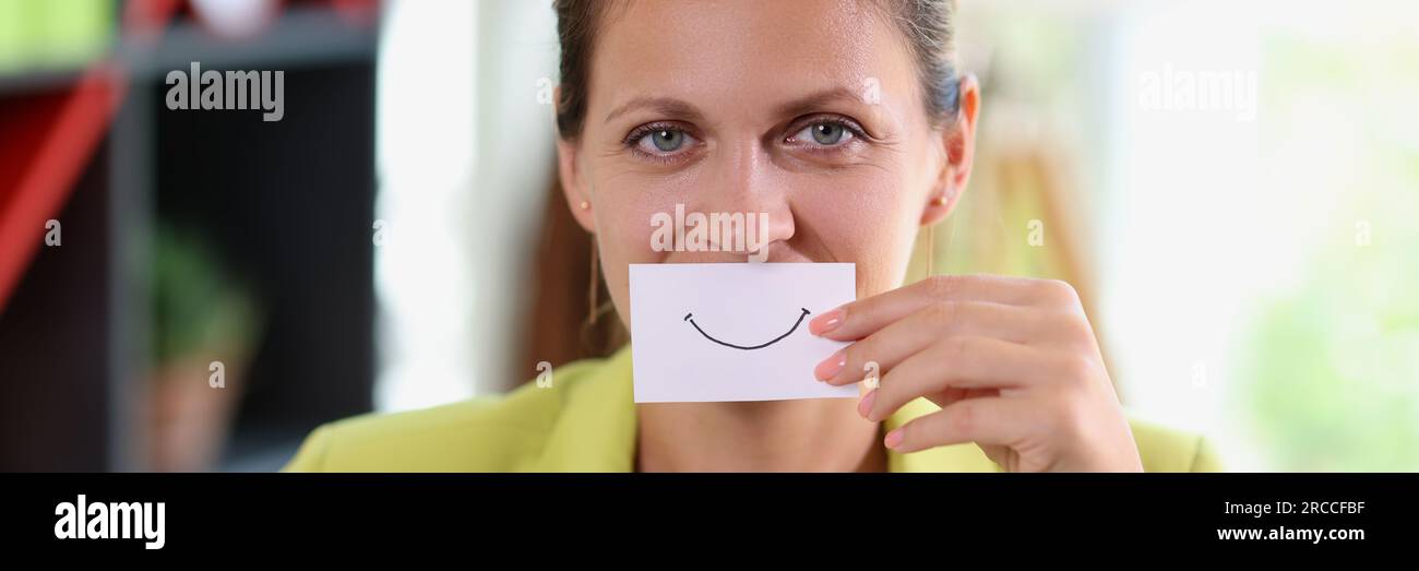 Woman in office holds paper with happy smile in front of her mouth ...