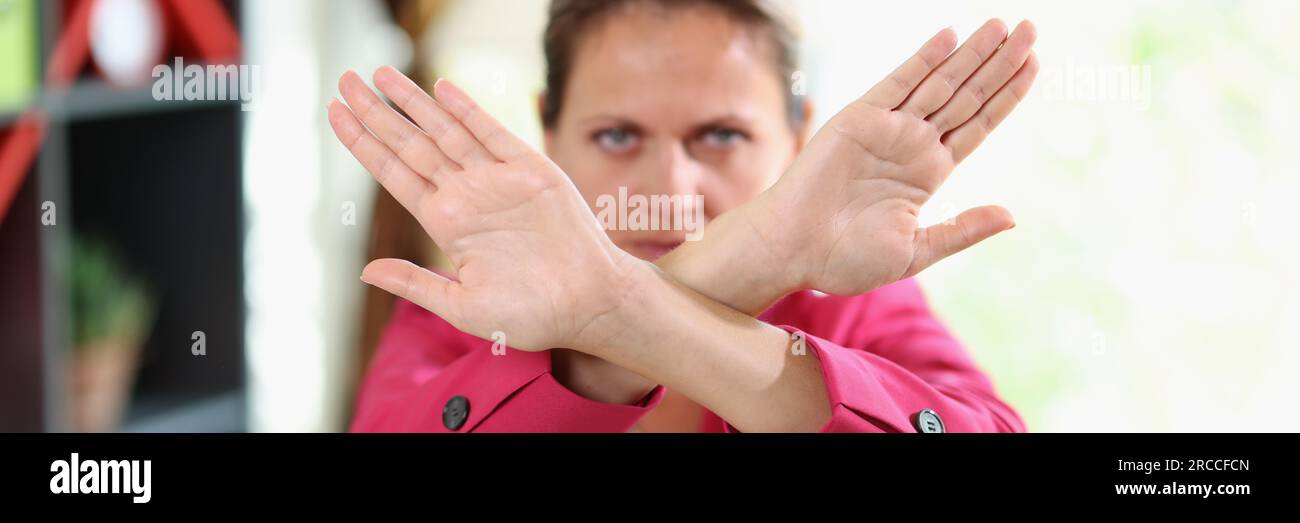 Woman with serious face shows crossed arms as symbol of no, stop ...