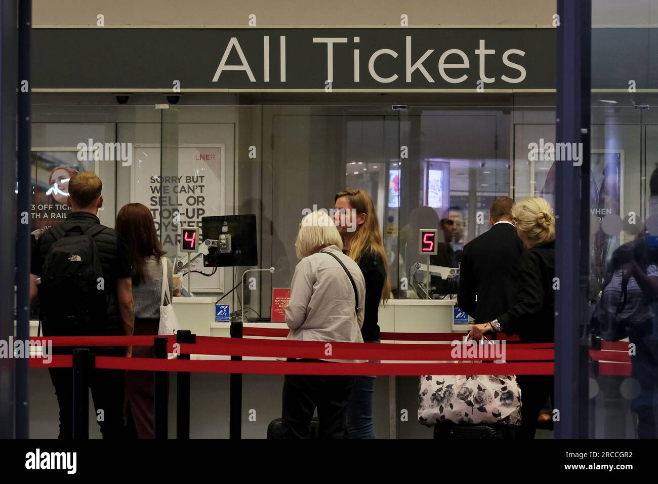 London, UK. People wait in line at King's Cross railway ticket office ...