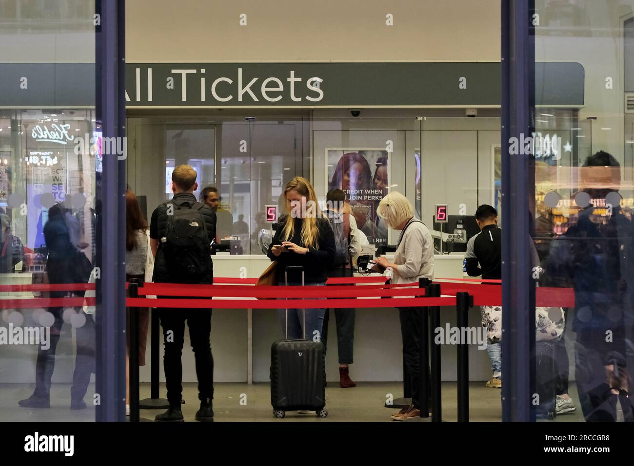 London, UK. People wait in line at King's Cross railway ticket office ...