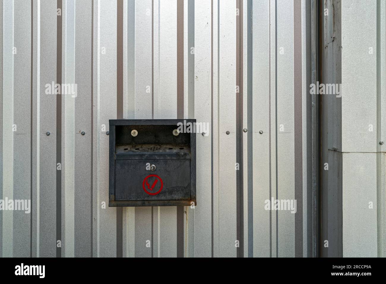 Ashtray mounted on an exterior corrugated metal wall Stock Photo - Alamy