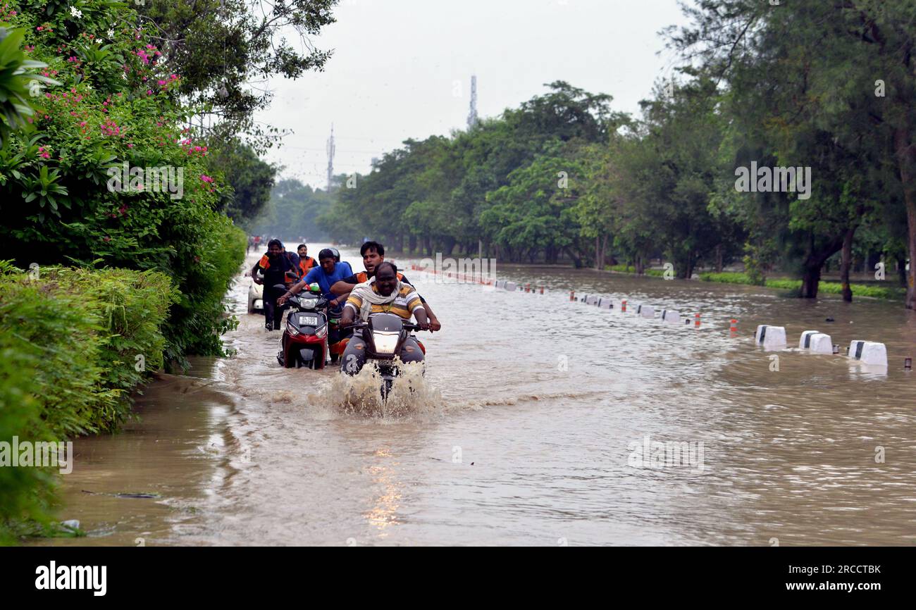 New Delhi, India. 13th July, 2023. People wade on a flooded road in New Delhi, India, July 13 ...