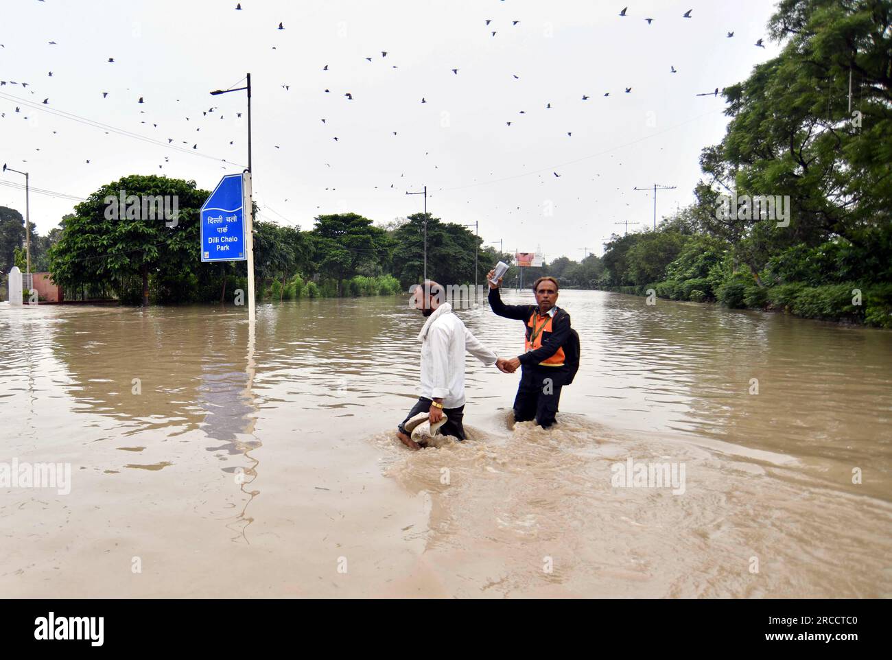 New Delhi, India. 13th July, 2023. People cross a flooded road in New Delhi, India, July 13 ...