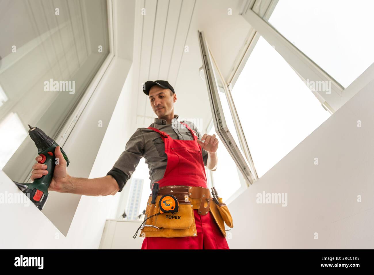 Construction worker using drill while installing window indoors Stock ...