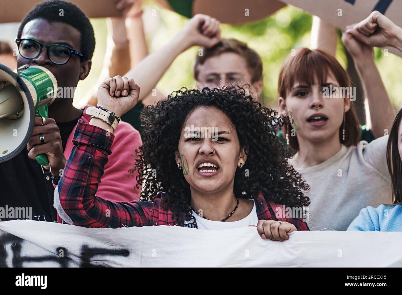 A curly-haired woman with a peace sign on her cheek, shouting and ...