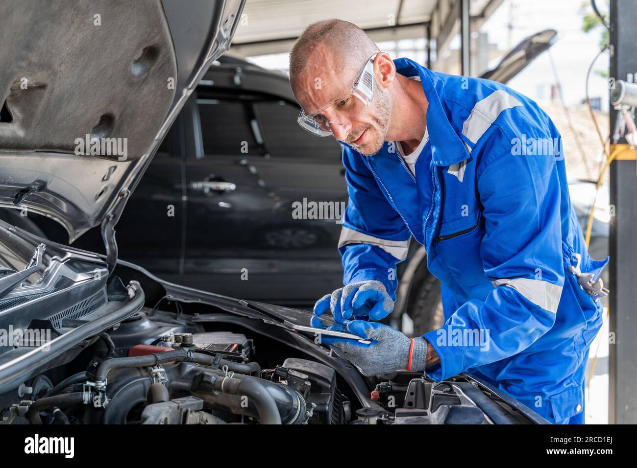 A male car mechanic using his computer tabet to check on the car's ...