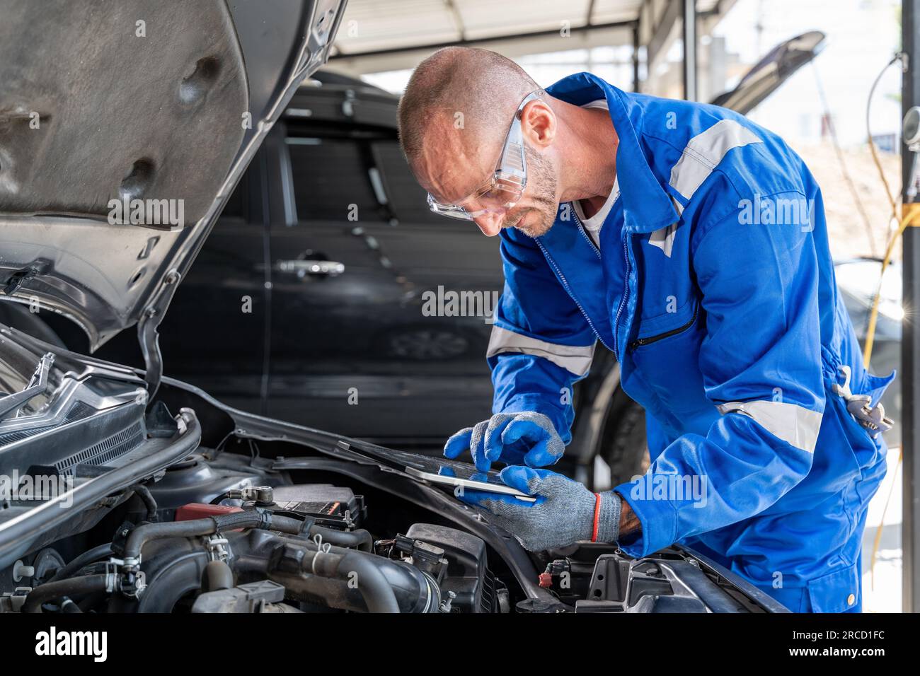 A male car mechanic using his computer tabet to check on the car's ...