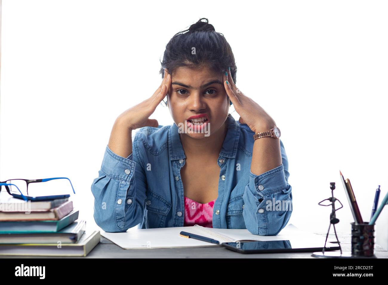 A pretty young Indian college student holding head for study load while ...