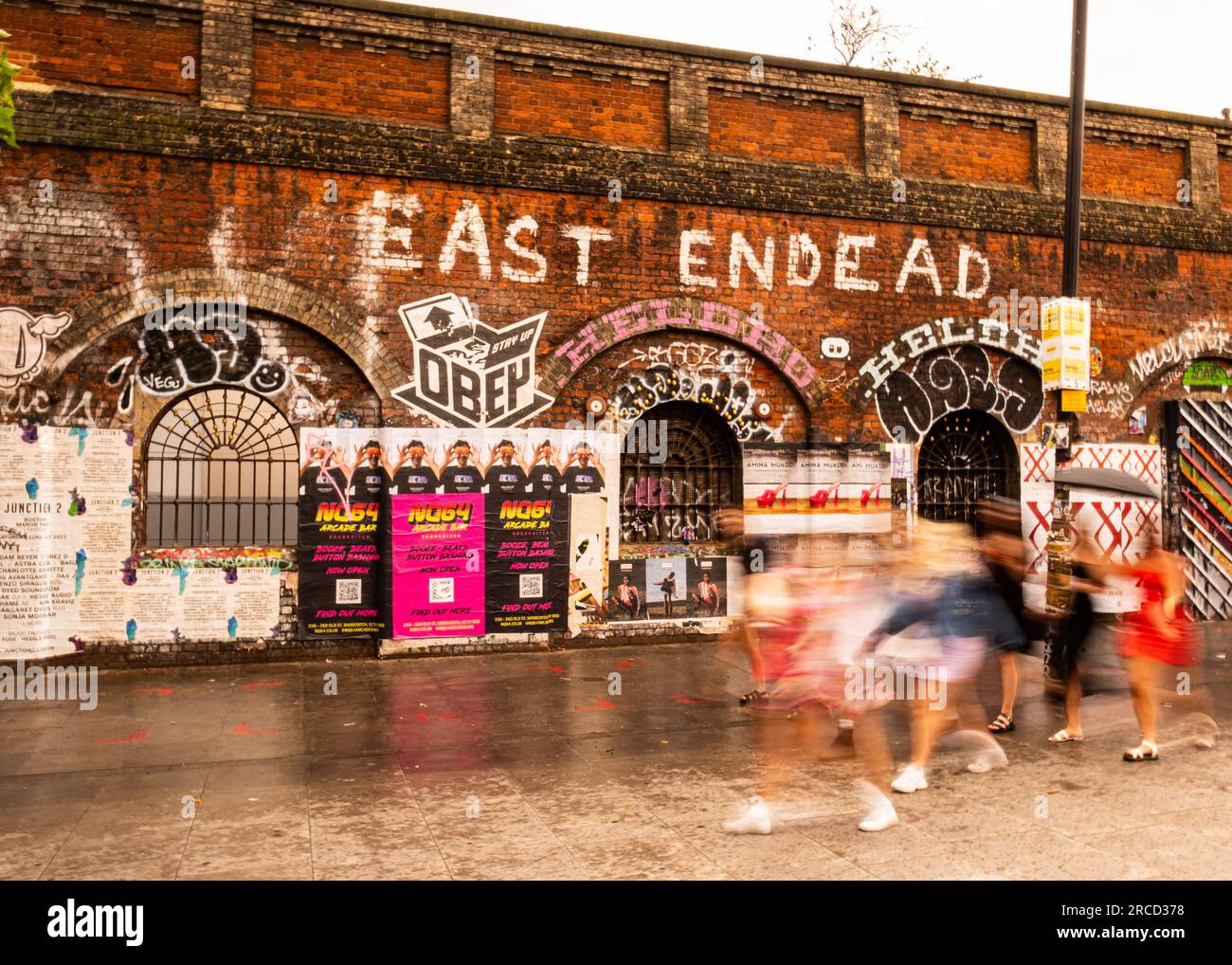 People walking in motion blur by Graffiti on buildings on a wet ...