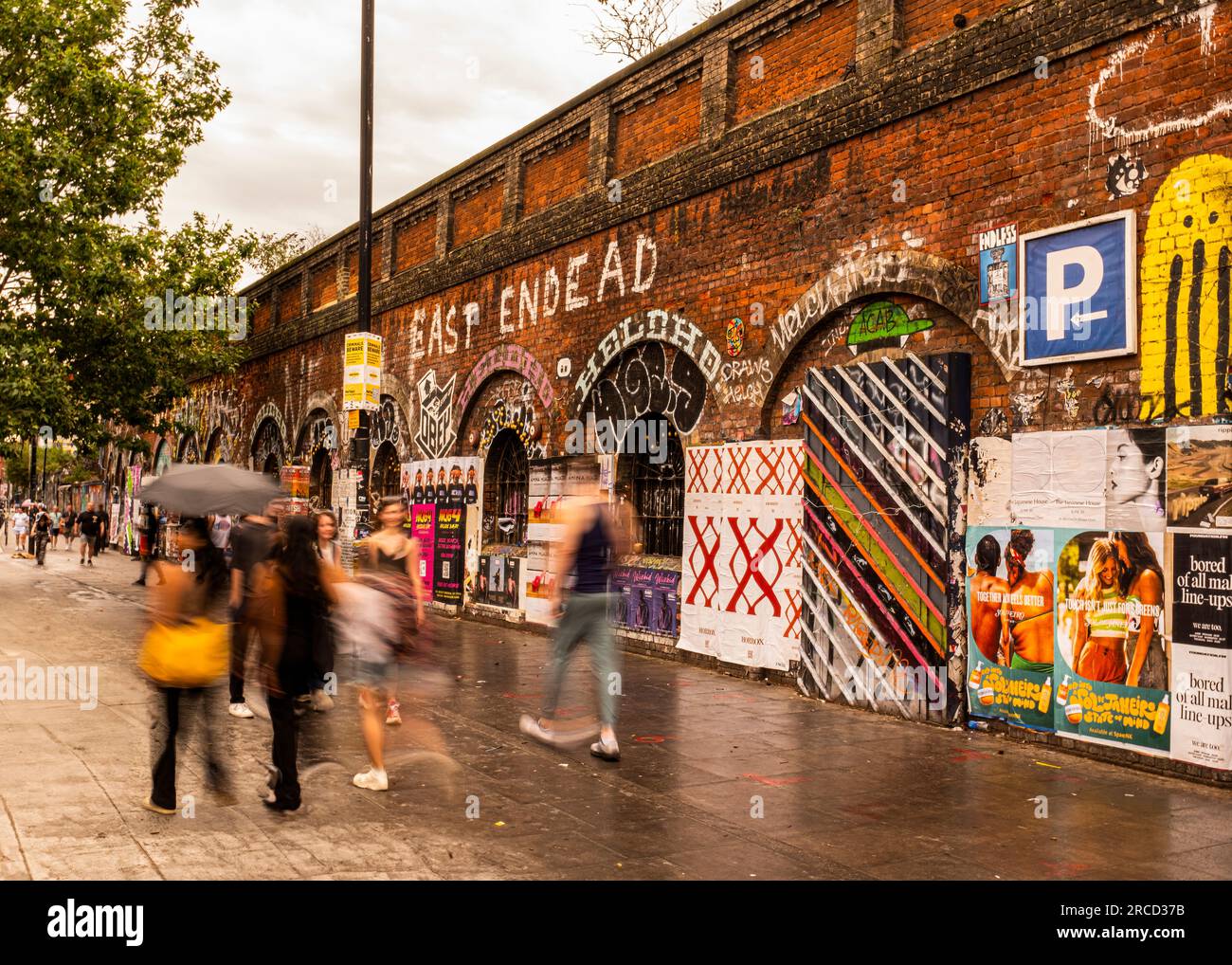 People walking in motion blur by Graffiti on buildings on a wet ...