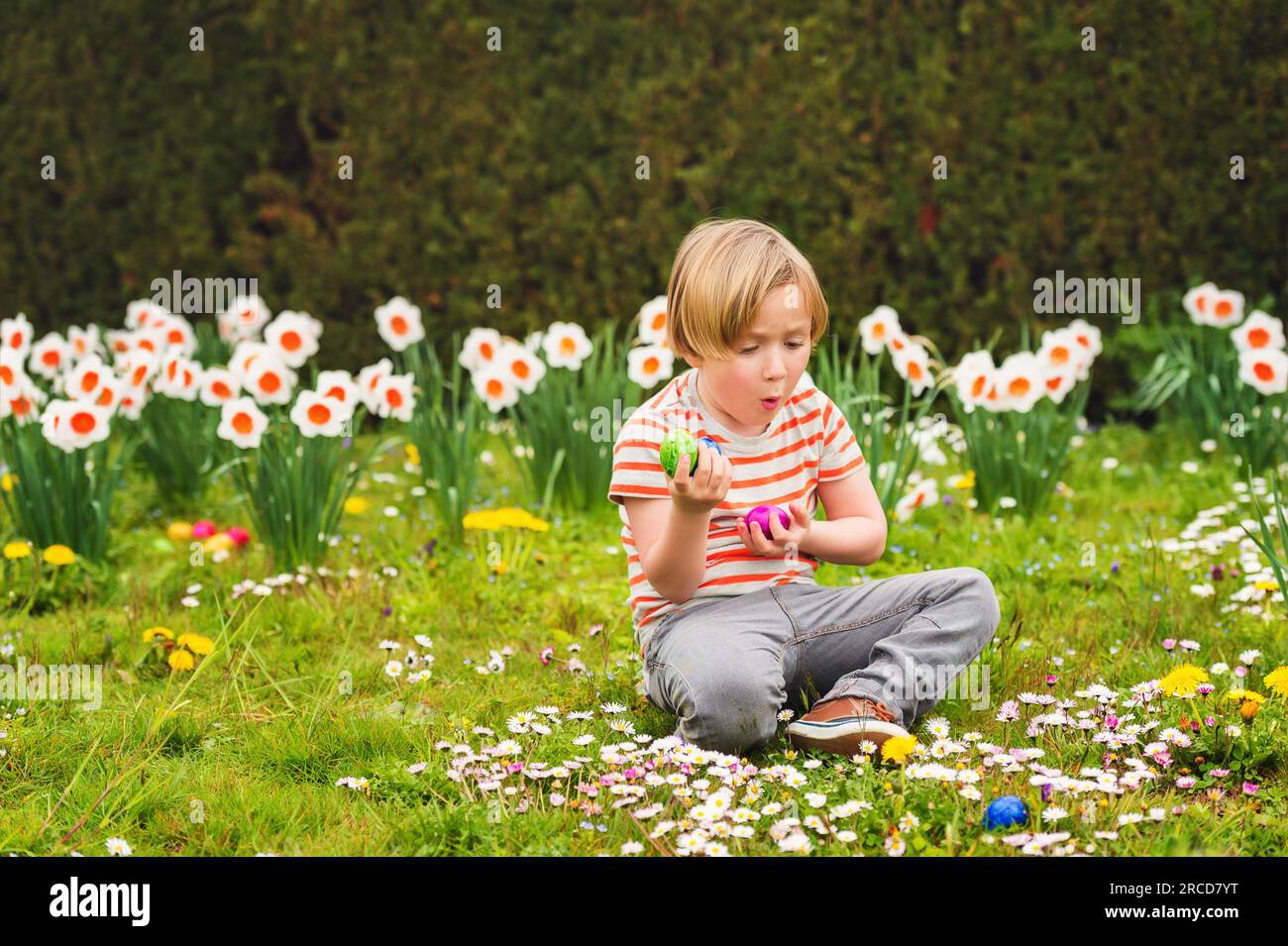 Adorable little blond boy playing with colorful easter eggs in the park ...