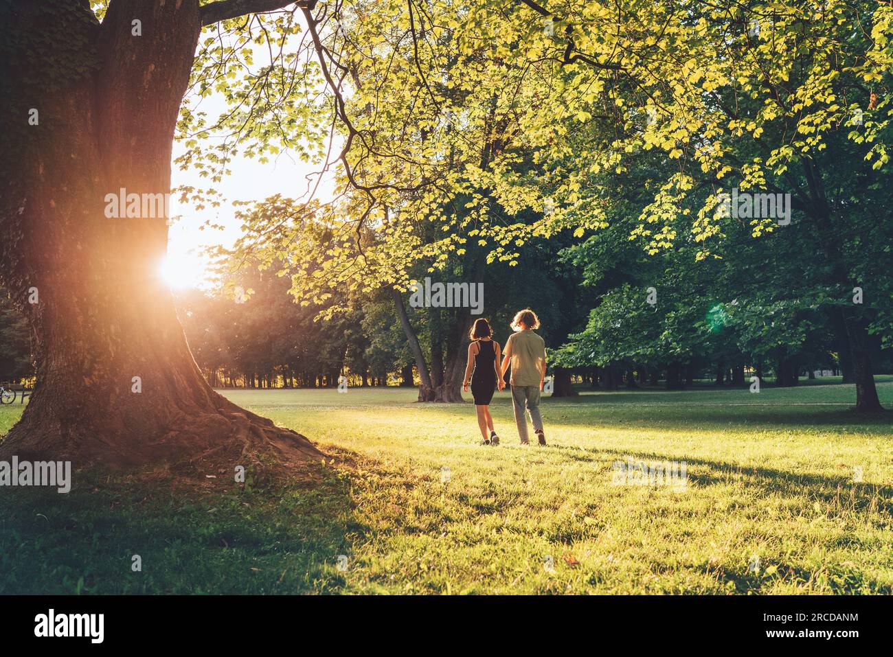 Young long-haired teenage boy with girlfriend walking hand in hand ...