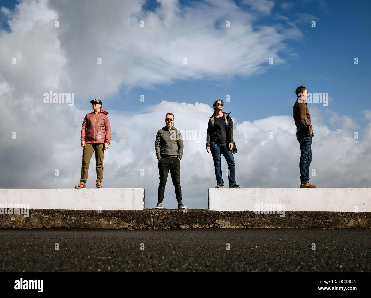 four friends stand on a white wall looking in different directions ...