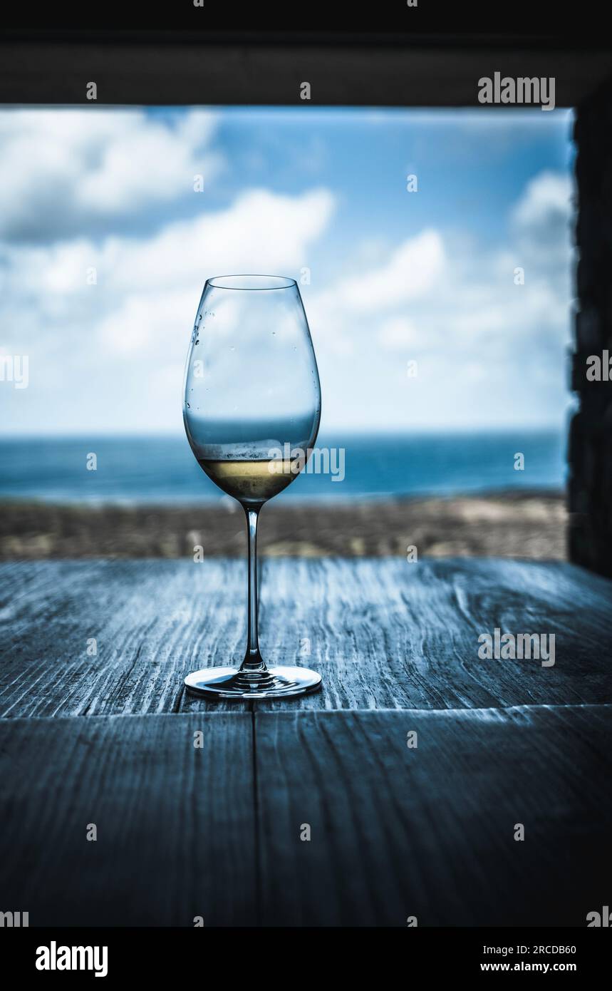 Glass of white wine on table in front of window with ocean view Stock ...