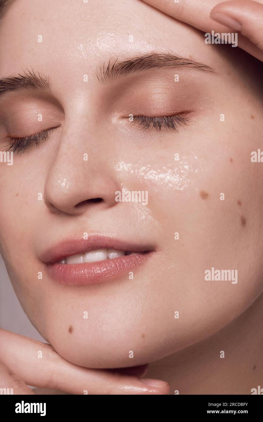 Face skin care. Woman applying a mask on clean hydrated skin portrait ...