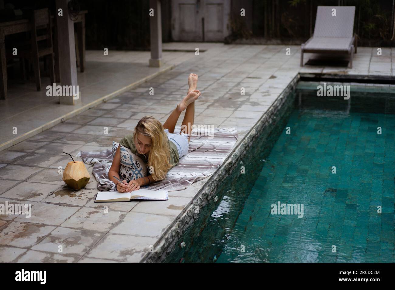 A young woman spends time by the pool, writing a diary Stock Photo - Alamy