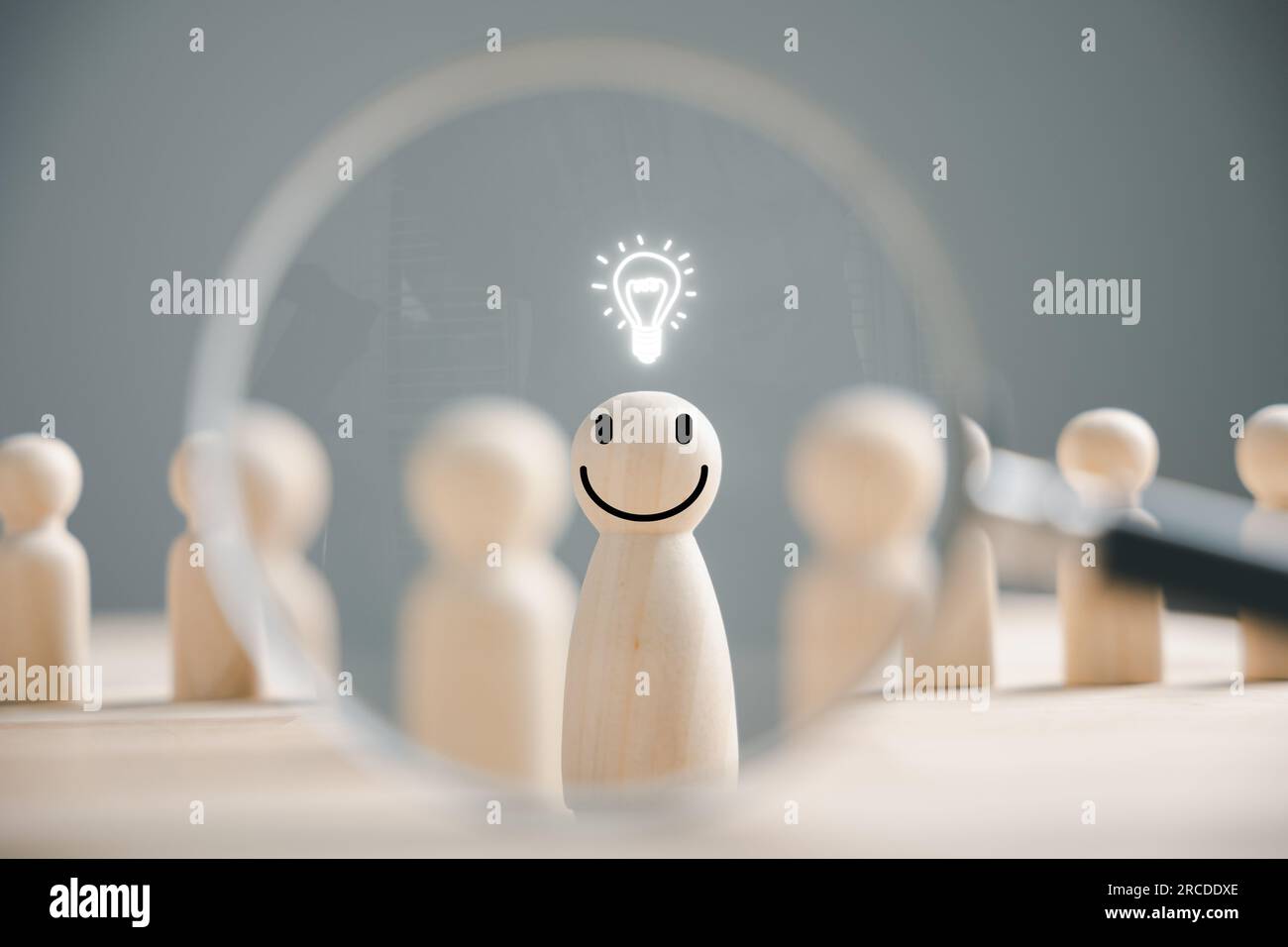 Magnifying glass uncovers a happy wooden person figure standing with a ...