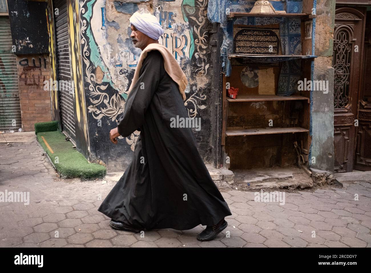 An old man with traditional clothes walks in the streets of Islamic ...