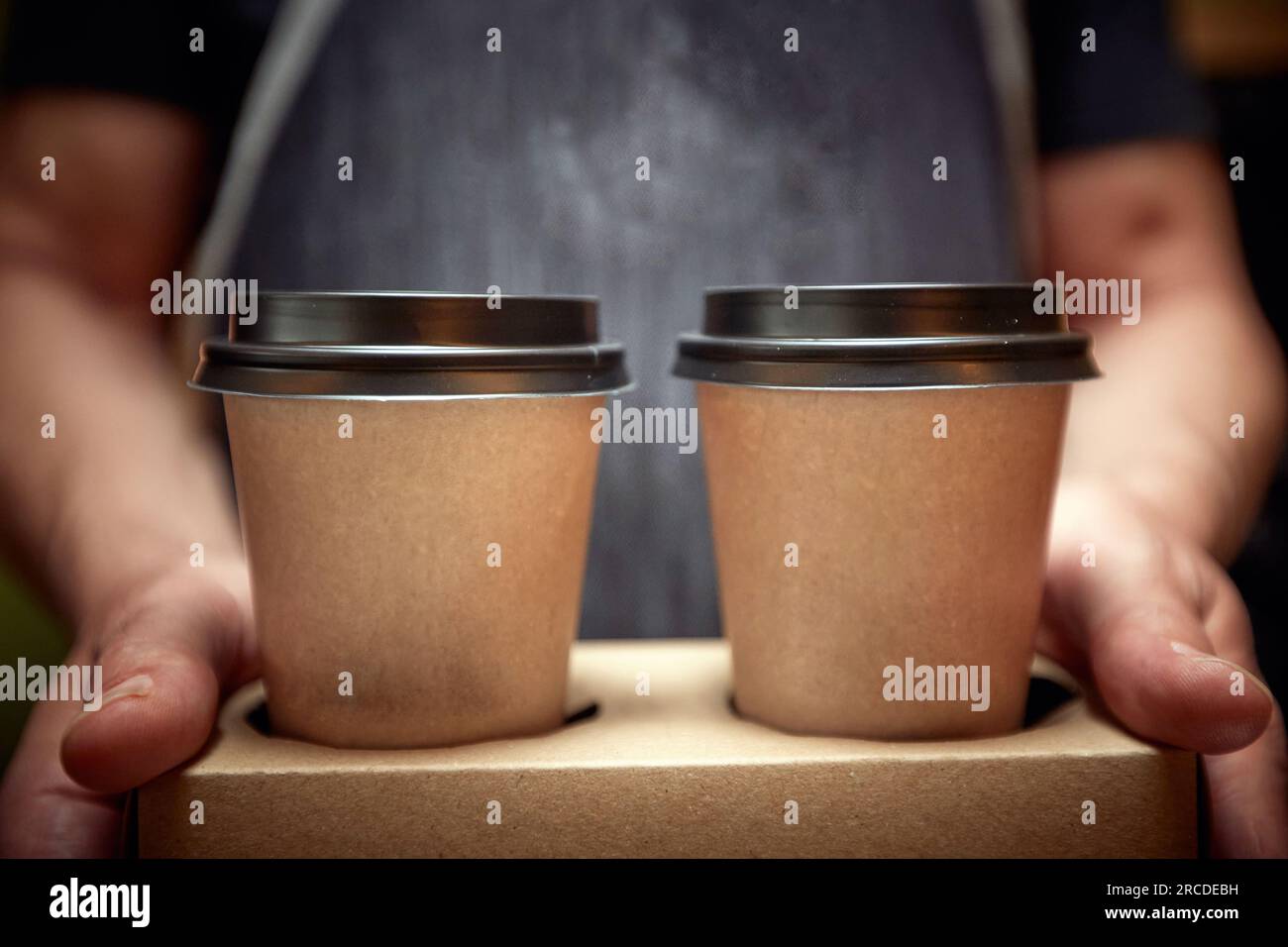 Detail of Caucasian man holding two coffees in cardboard cup, showing ...