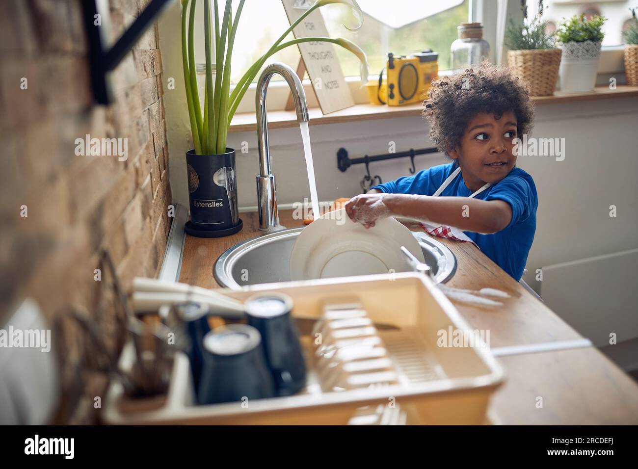 Young Afro-American boy takes on the responsibility of washing dishes ...