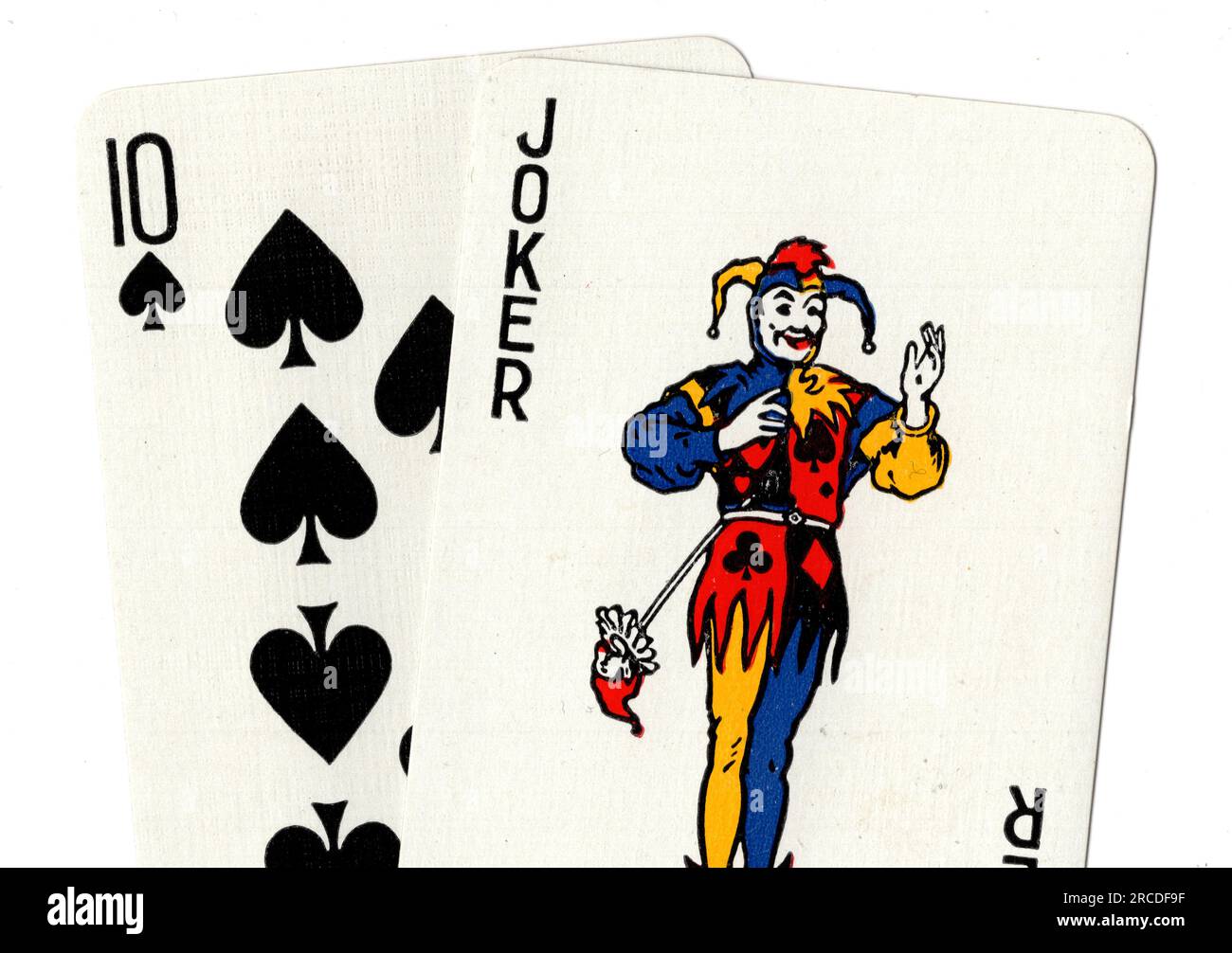 Vintage playing cards showing a joker and a ten of spades on a white ...
