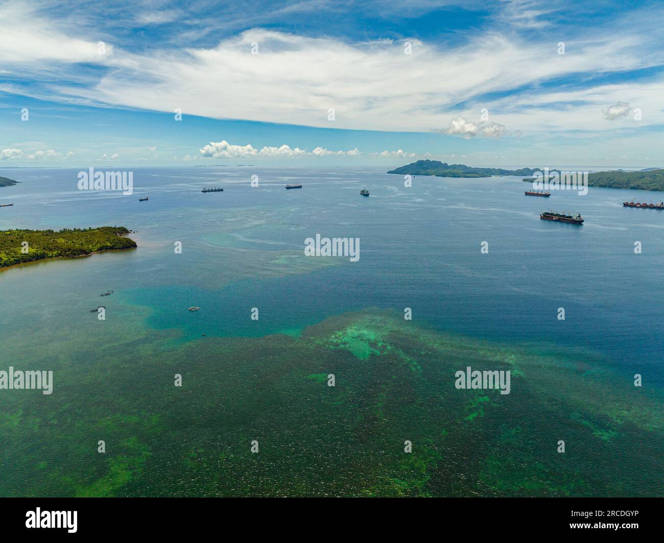 Turquoise water with cargo and merchant ship. Blue skies and clouds ...