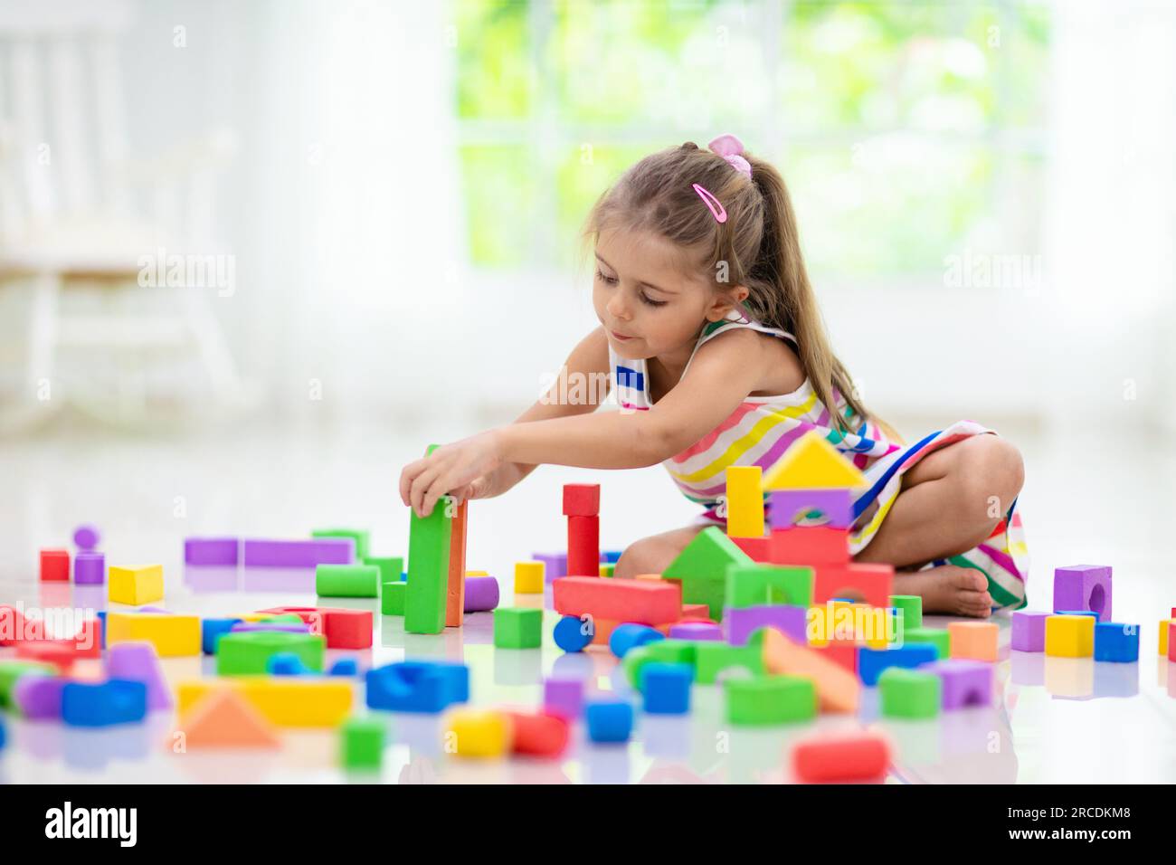 Kids play with colorful blocks. Little girl building tower at home or ...