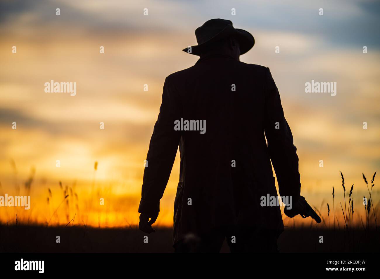 Silhouette of a cowboy in a hat with a revolver against a dramatic ...