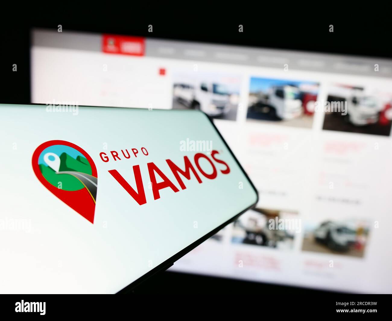 Mobile phone with logo of Brazilian truck rental company Grupo Vamos on screen in front of ...