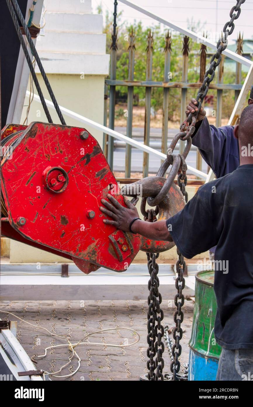 african worker using a chain to secure a crane hook Stock Photo - Alamy