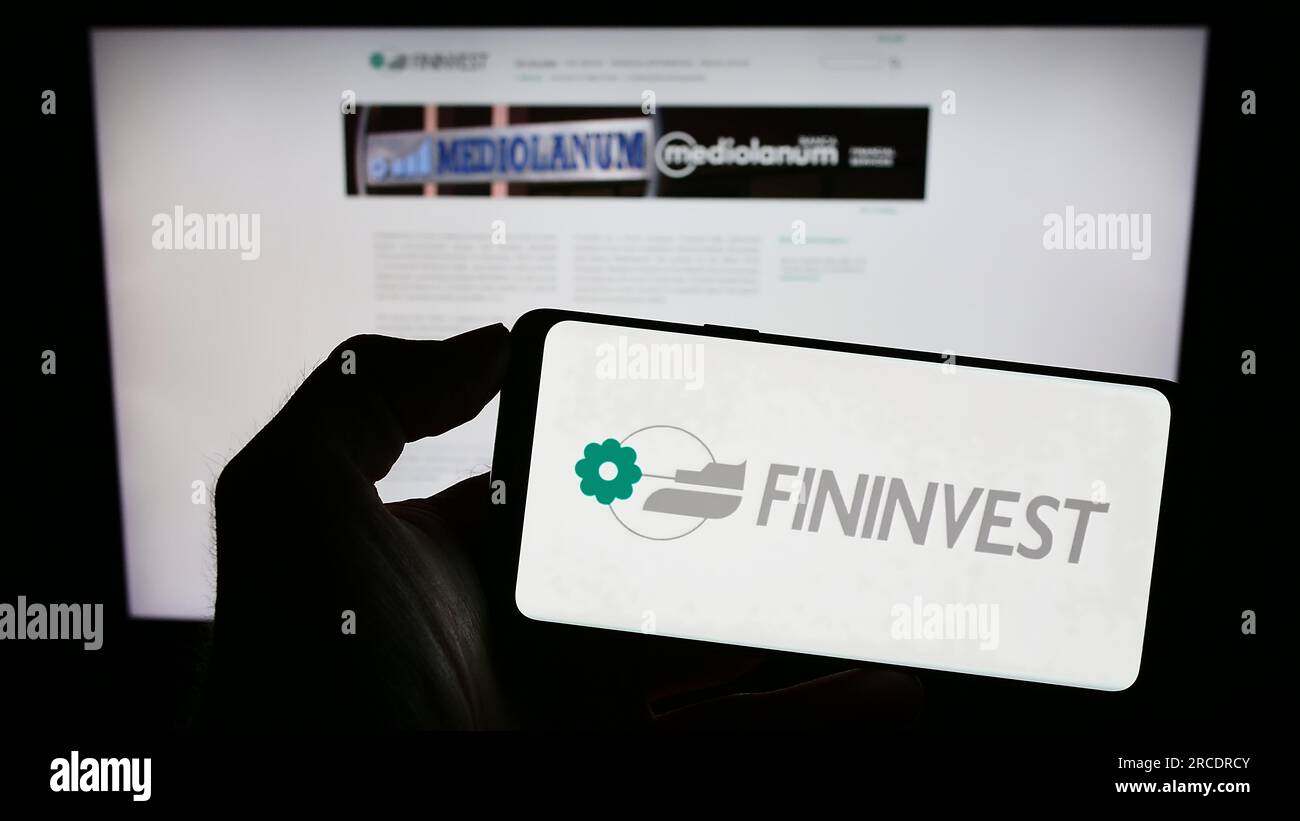 Person holding cellphone with logo of Italian holding company Fininvest ...