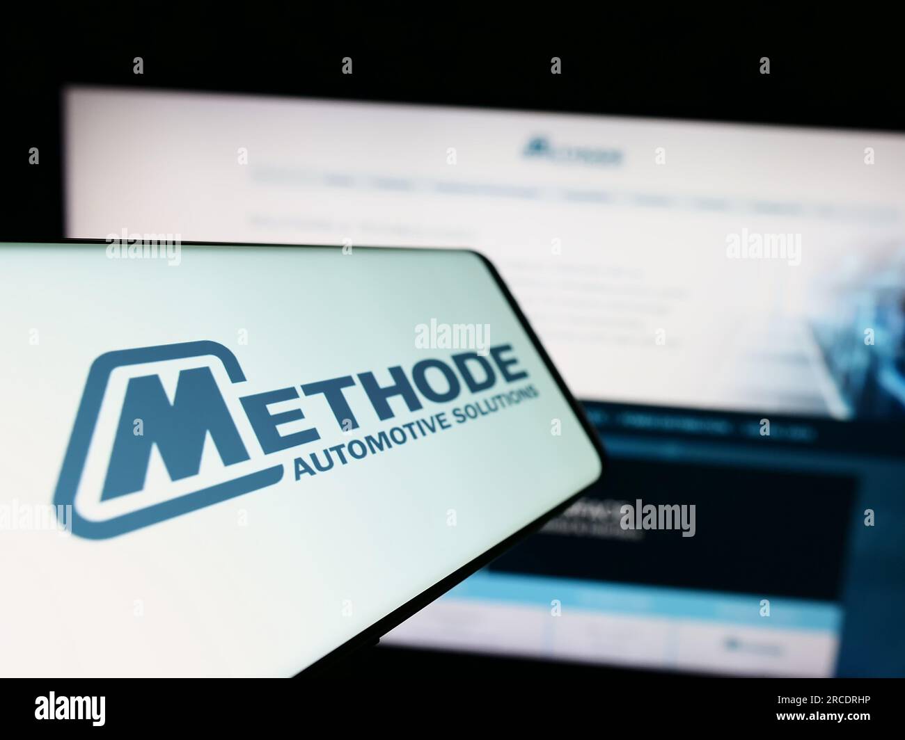 Mobile phone with logo of American company Methode Electronics Inc. on screen in front of ...